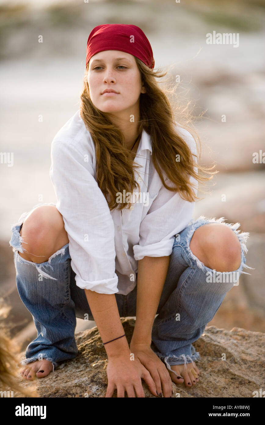 Young woman with bandana crouching on rock Stock Photo - Alamy