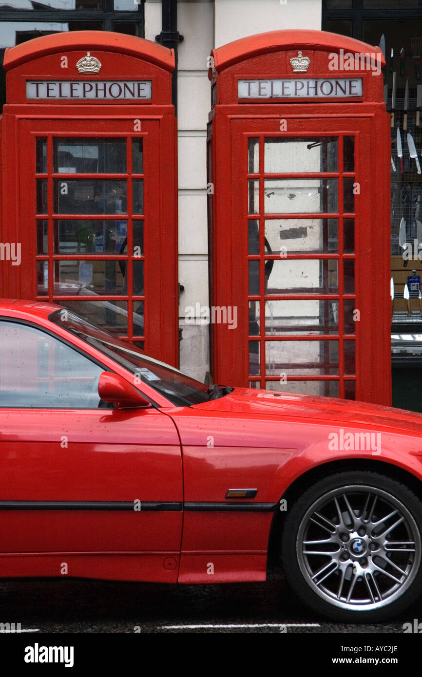 Two of the iconic red London telephone boxes with a red car parked ...