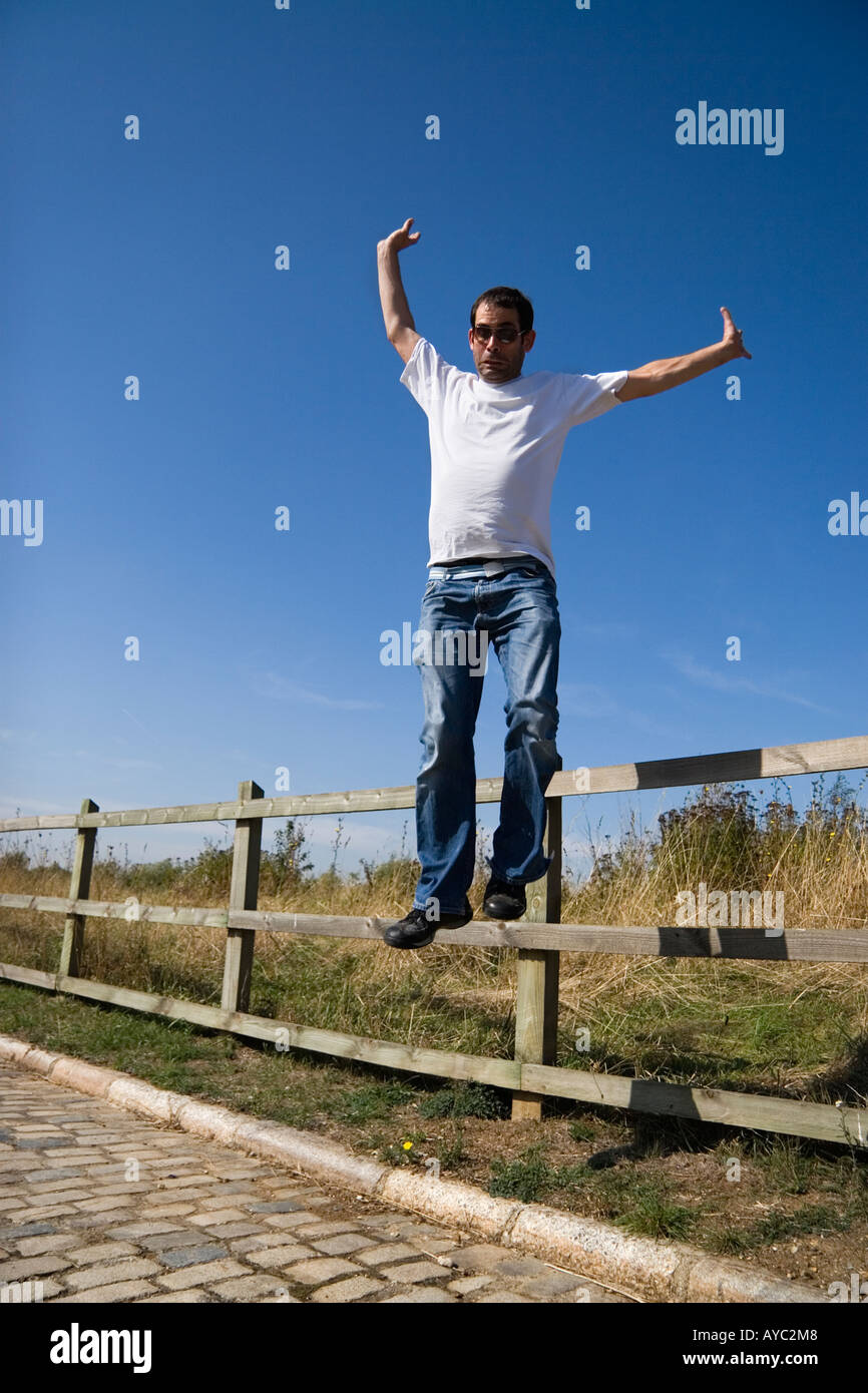 a man jumping off a wooden fence on to a cobbled path Stock Photo - Alamy