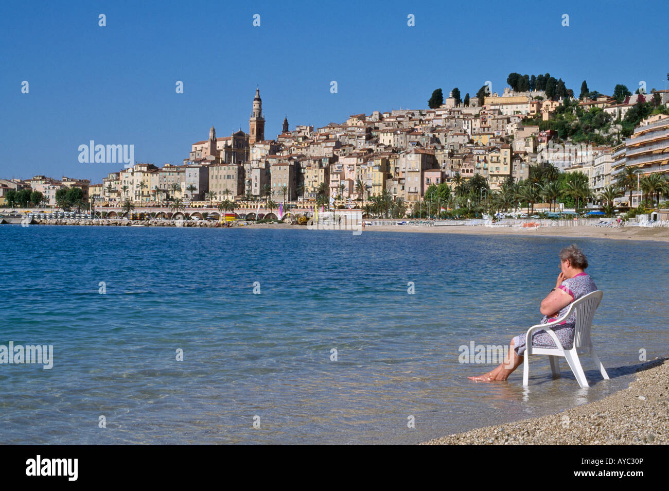 Elderly woman sitting on chair on beach at Menton Alpes Maritimes ...