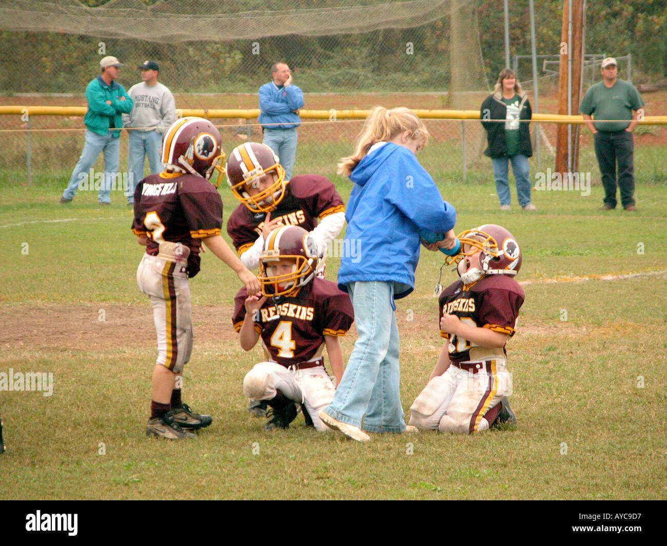 female real coach helping her Kids learn during full contact football ...