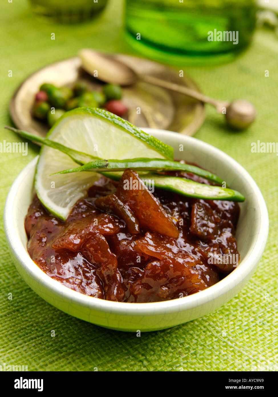 A bowl of lime and chili chutney with a green background table setting ...