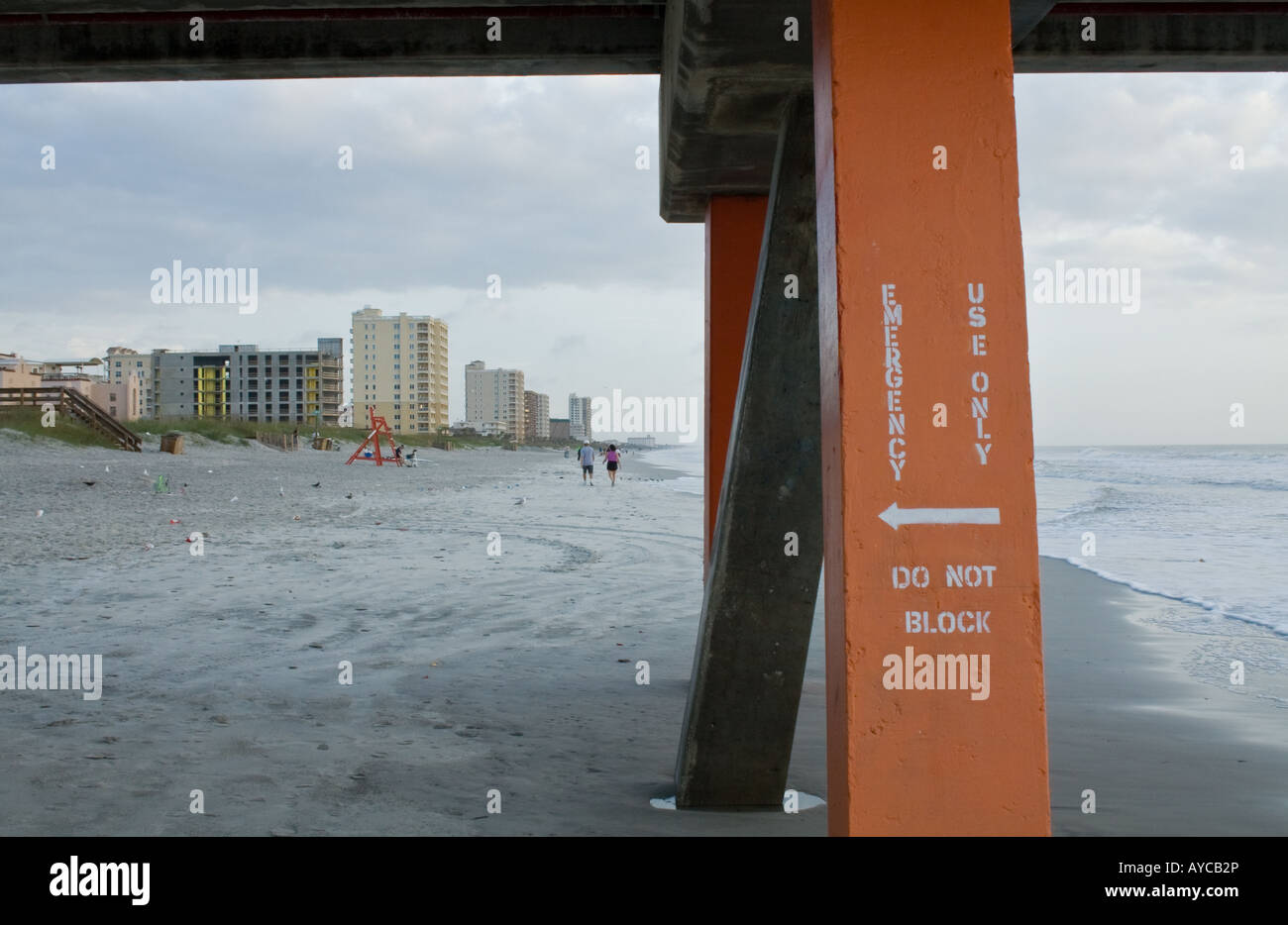 Emergency warning sign under a pier with building in the background on ...