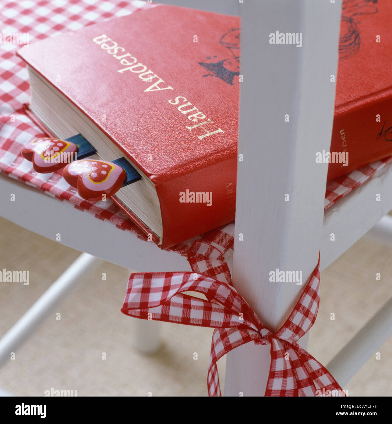 Childrens story book on chair with gingham ribbon Stock Photo - Alamy