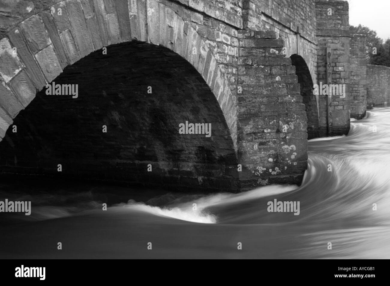 River water rushing under the arches of an old stone bridge Stock Photo ...