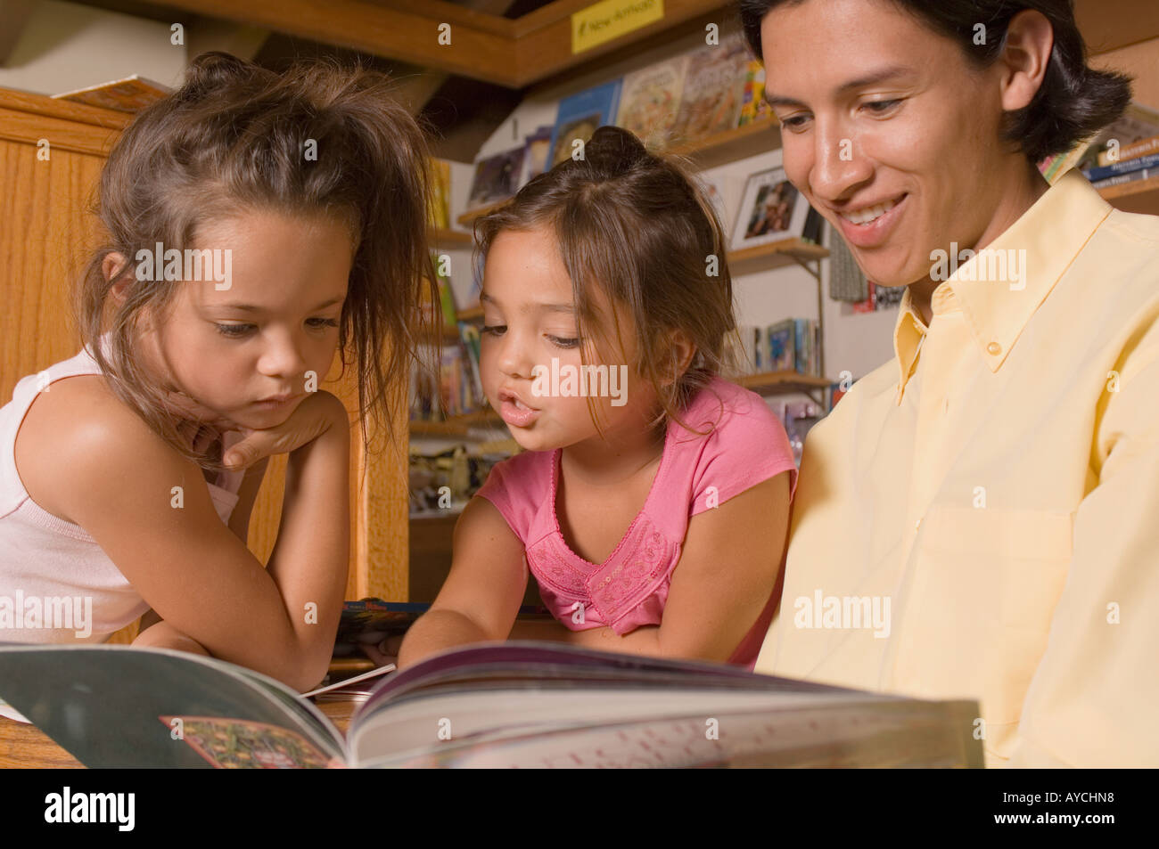 Brother reading to twin sisters Stock Photo - Alamy