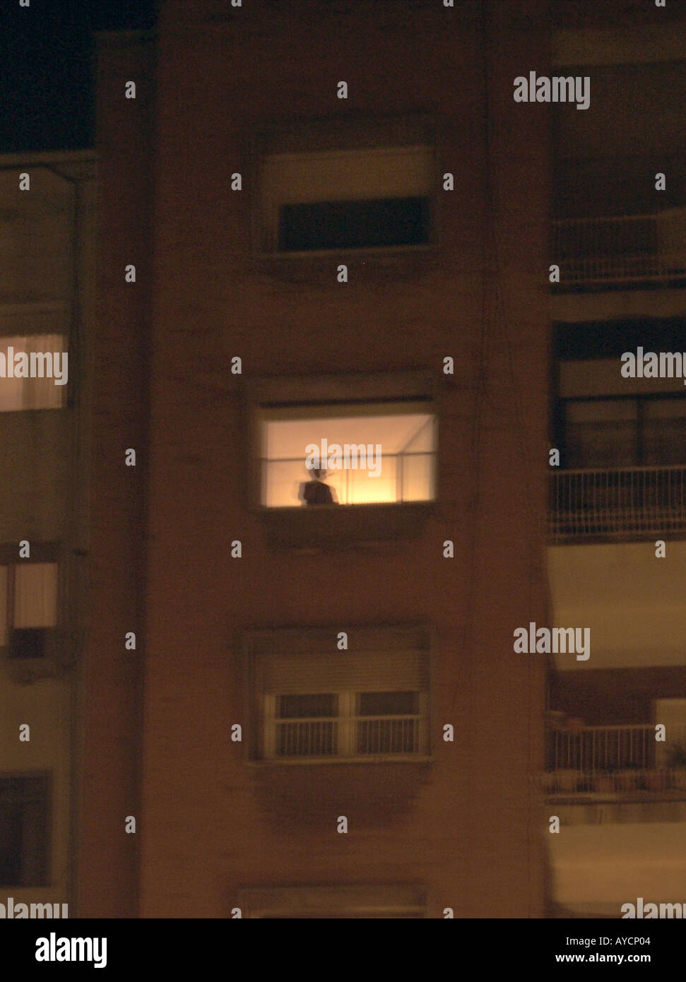 person looking out of apartment office window at night Stock Photo - Alamy