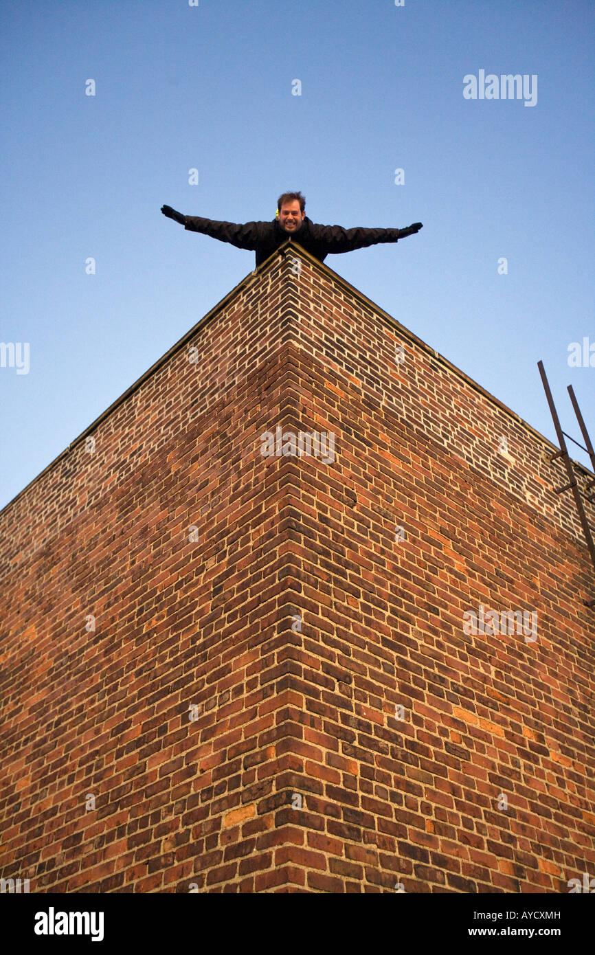 Man hangs over edge of roof and pretends to fly Stock Photo - Alamy