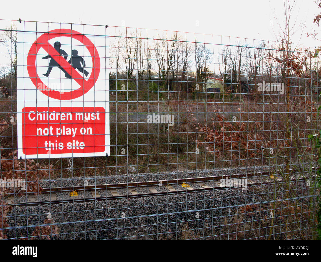 A sign on a chain linked fence telling children not to play on rail way lines Stock Photo - Alamy