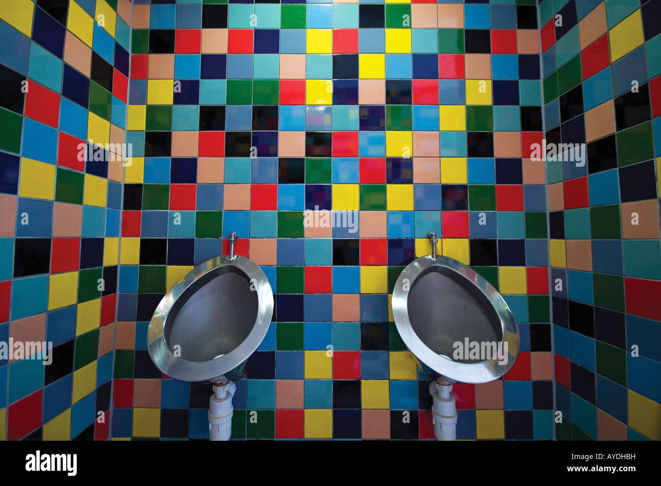 Two silver stainless steel urinals in public toilets with walls covered ...