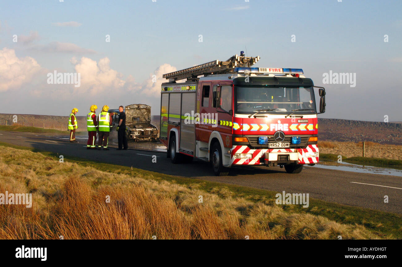 Firemen and a fire engine next to a burnt out car on Moorland in the ...