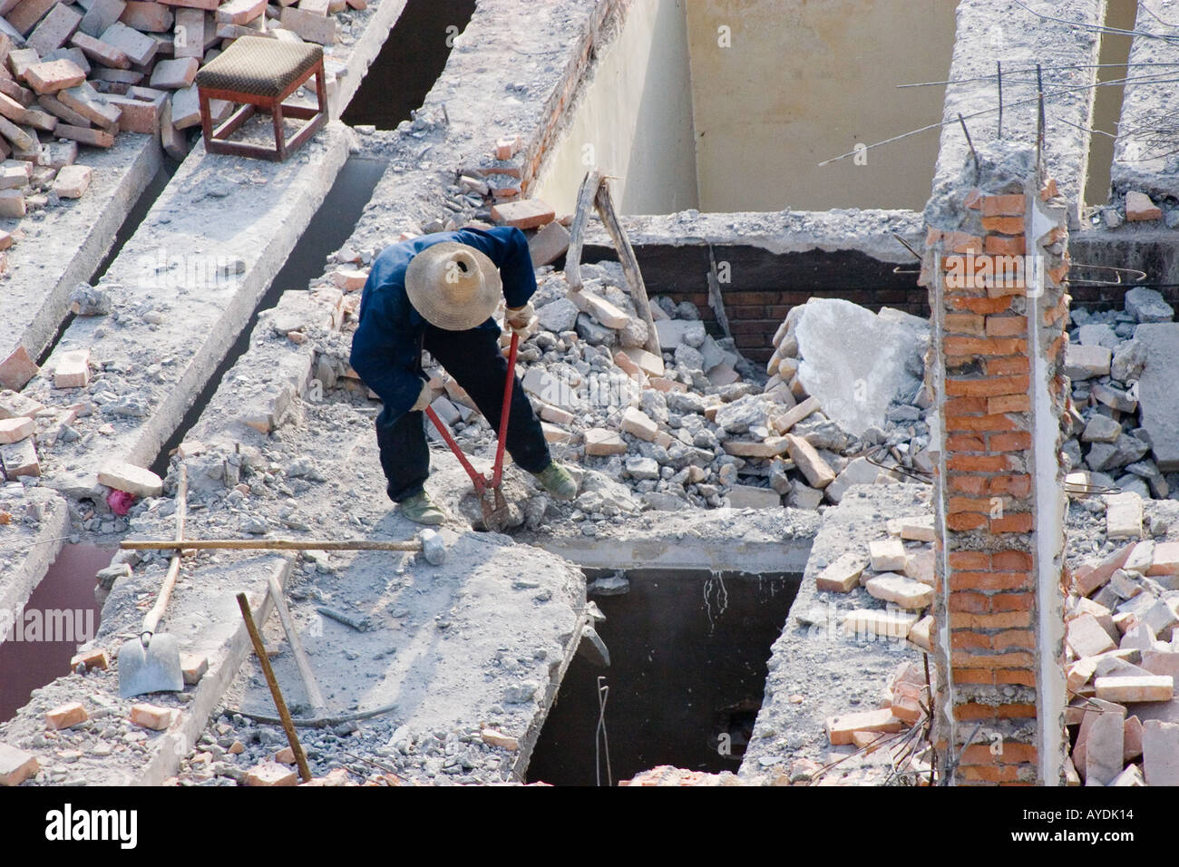Chinese laborer with bolt cutters working on a building being torn down ...