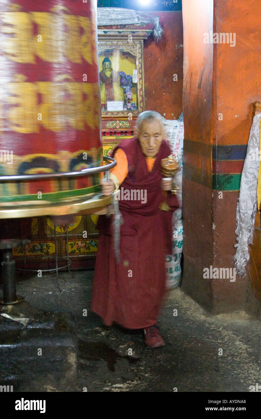 Tibetan priest turning a large prayer wheel in a monastary in Lhasa ...