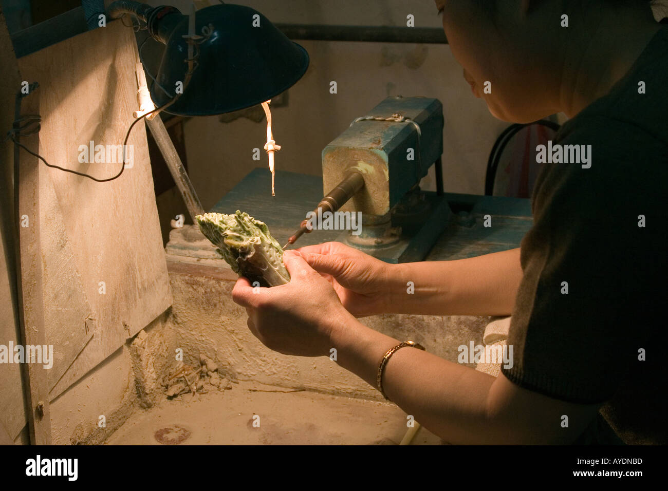 Chinese craftswoman carving a jade statue in a small jade factory in Xi ...