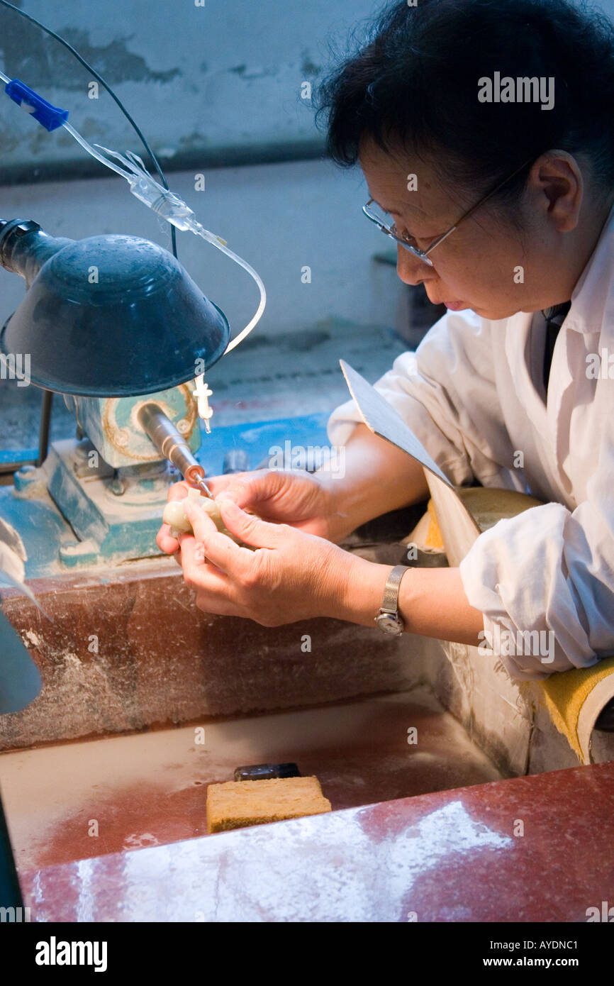 A chinese artist carves a jade Buddha in a small jade factory located ...