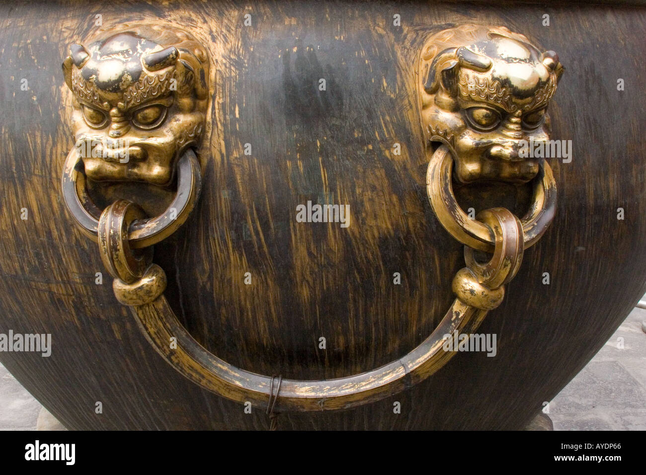 Carved brass heads forming a giant handle on a huge incense pot in the ...