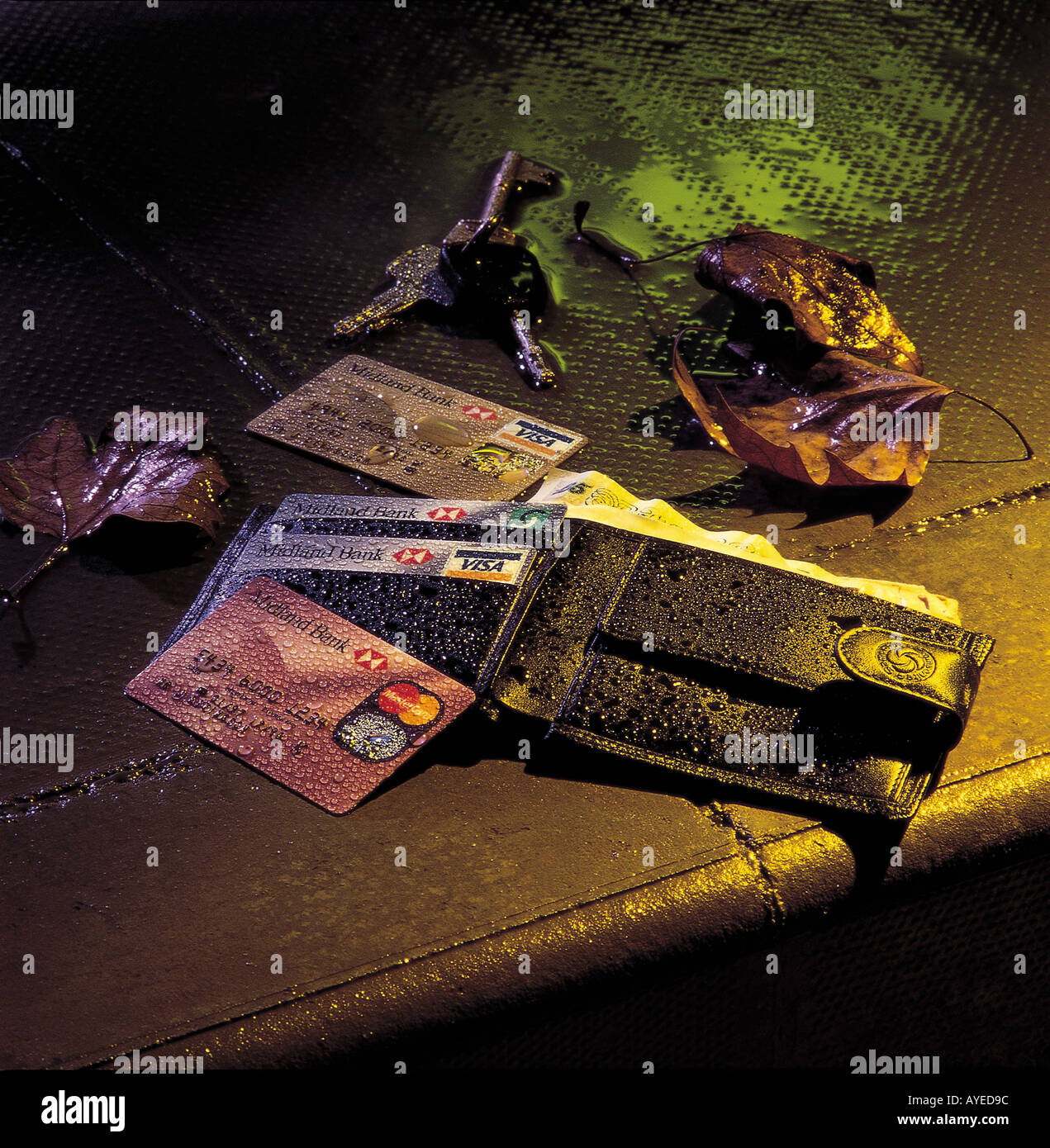 a lost wallet fallen on a wet pavement sidewalk at night with keys and ...