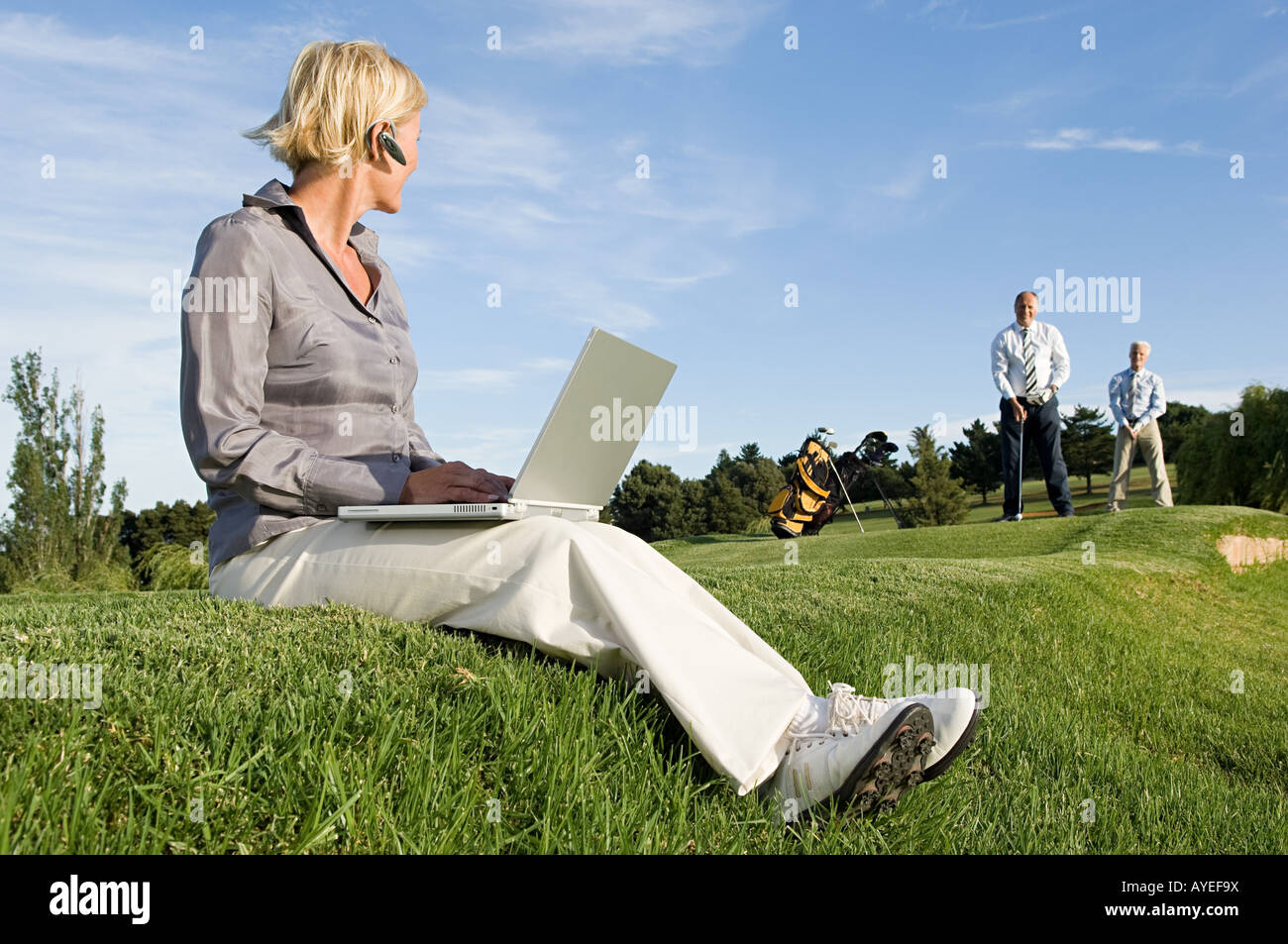 A businesswoman watching colleagues playing golf Stock Photo - Alamy