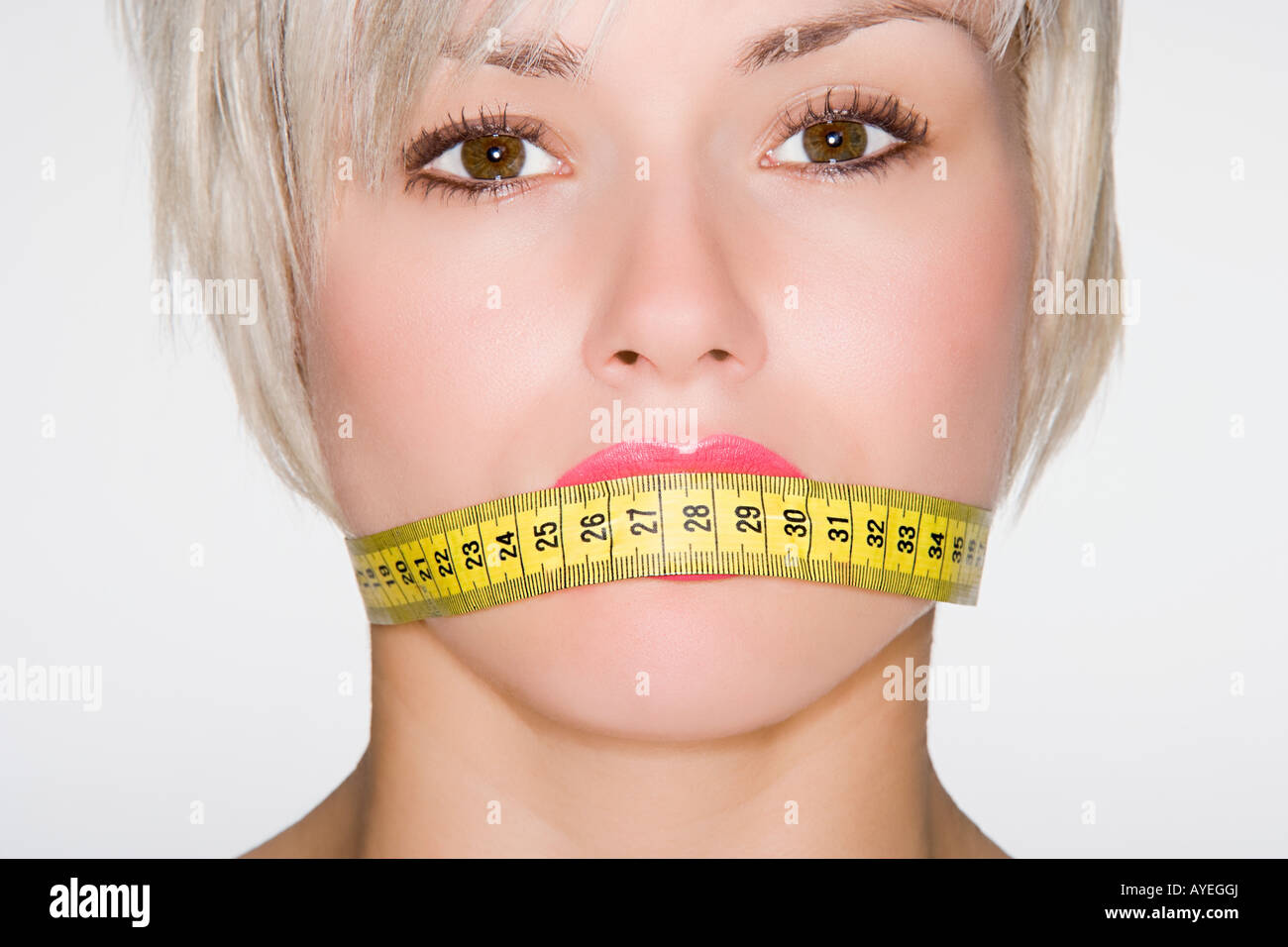 Woman with tape measure over her mouth Stock Photo - Alamy