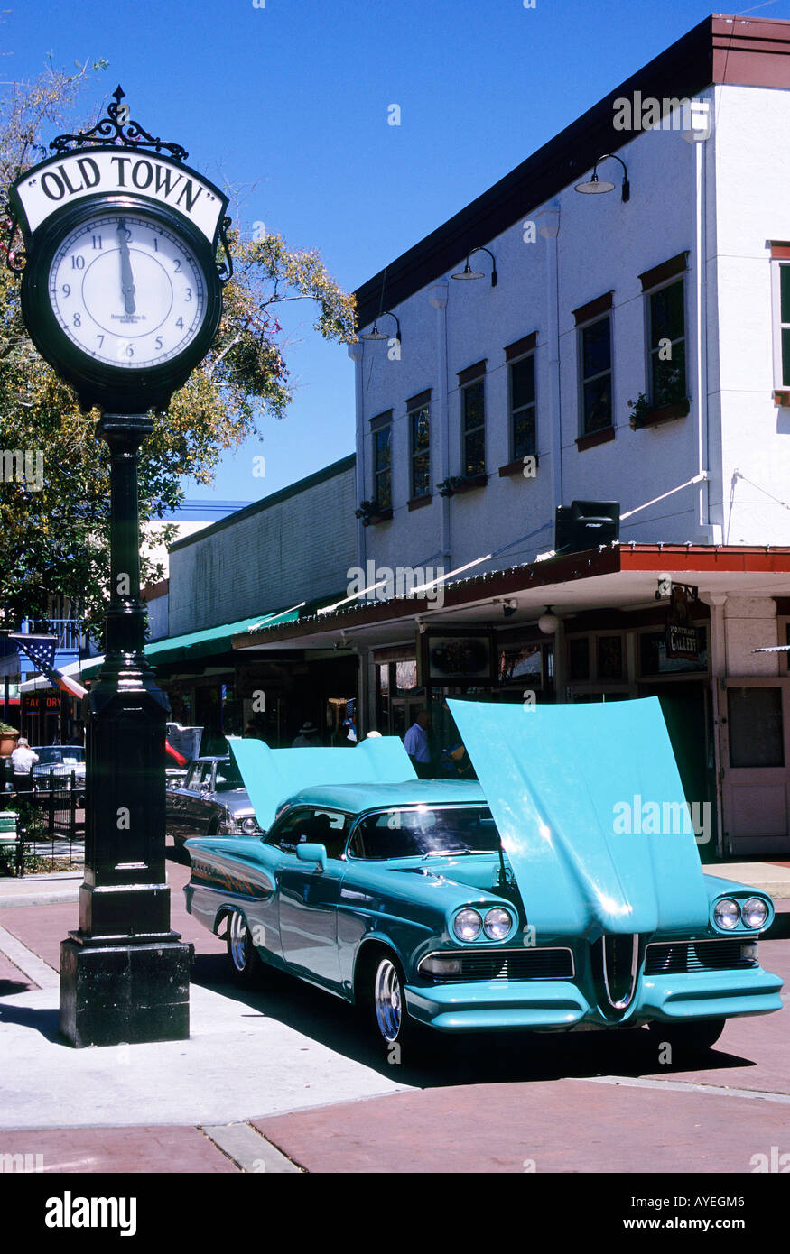 A blue classic car with the boot and bonnet open parked beside a clock ...