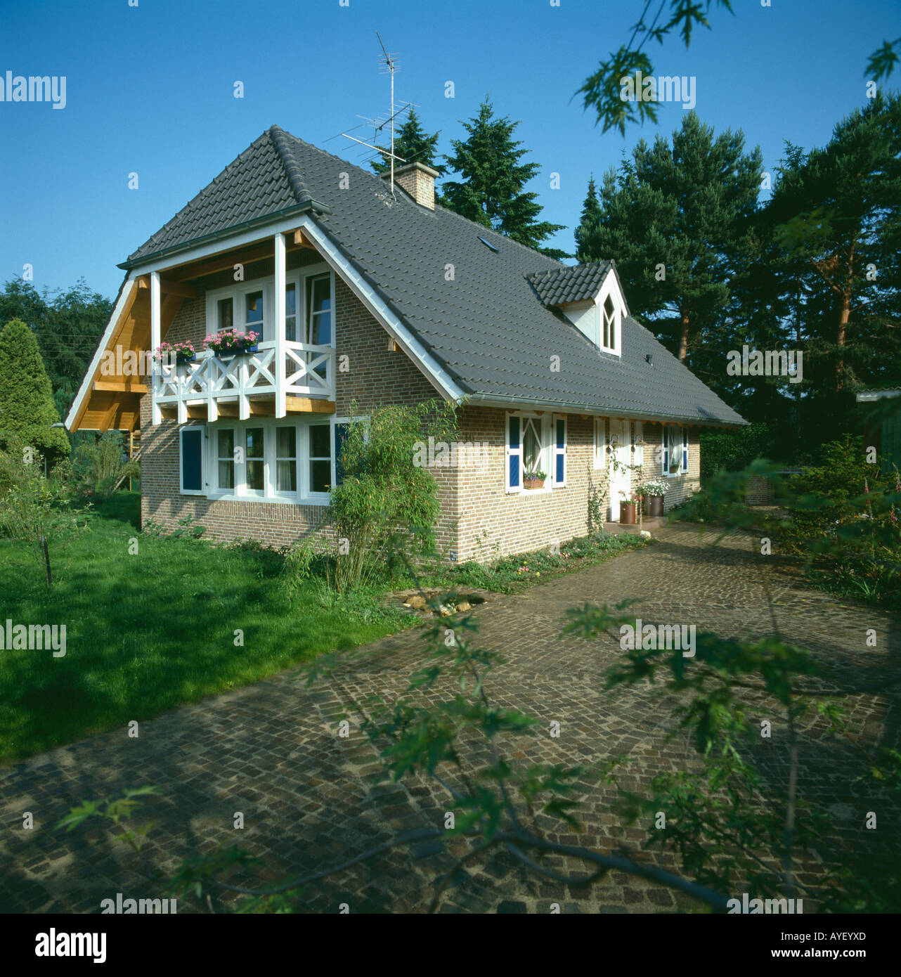 Traditional German country cottage with balcony and paved area in front ...