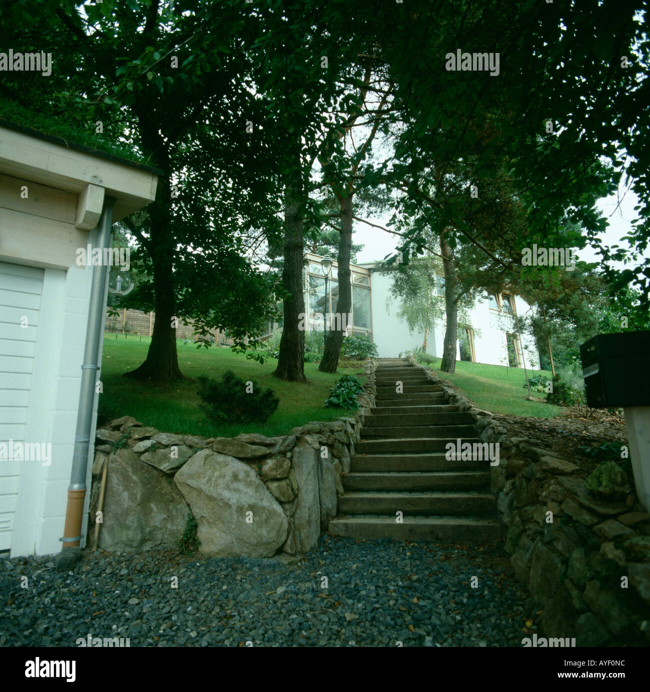Stone steps through trees in large hillside country garden with rough ...