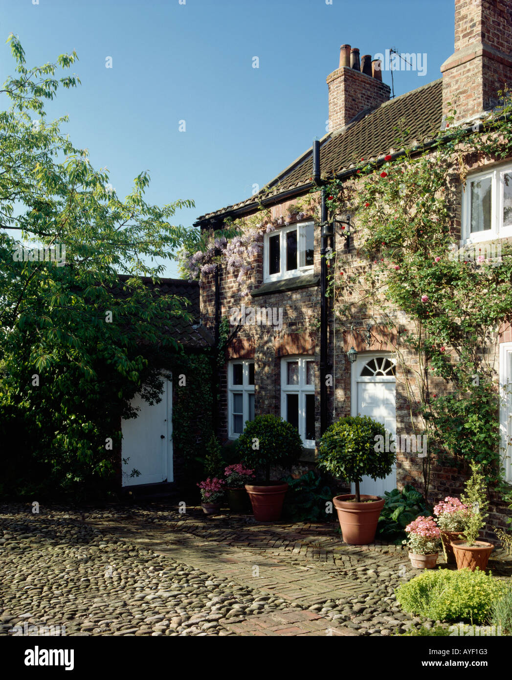 Paved courtyard in front of small country house Stock Photo - Alamy