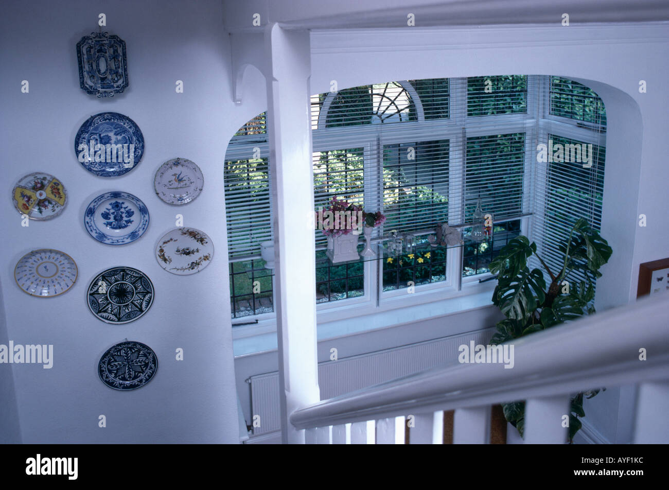 Landing with plates on wall beside window Stock Photo - Alamy