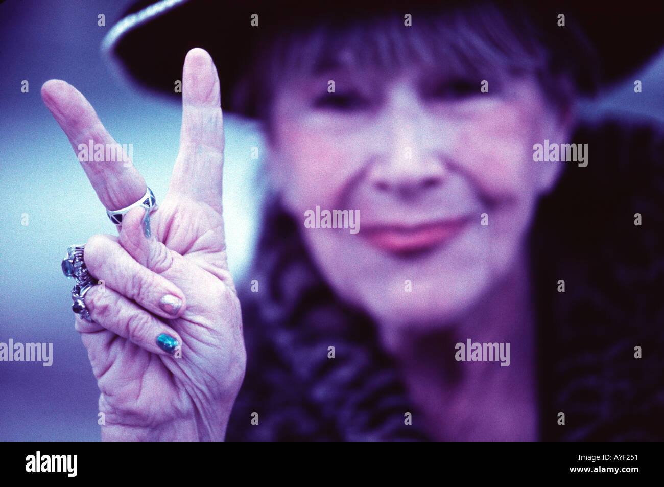 Older woman smiling and holding up peace sign Stock Photo - Alamy