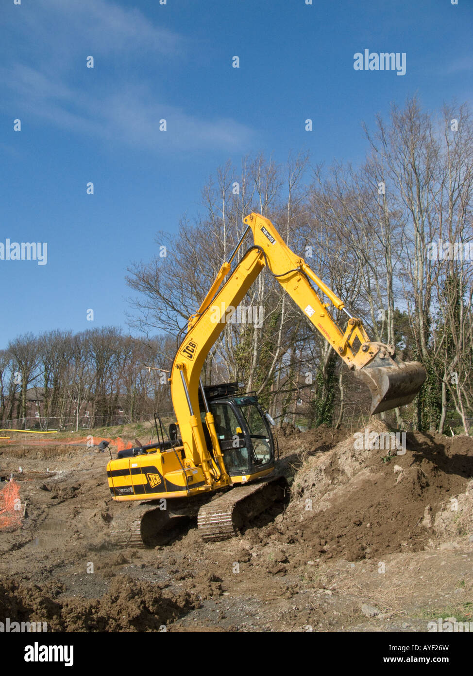 A yellow JCB digger clearing land in preparation for building work ...