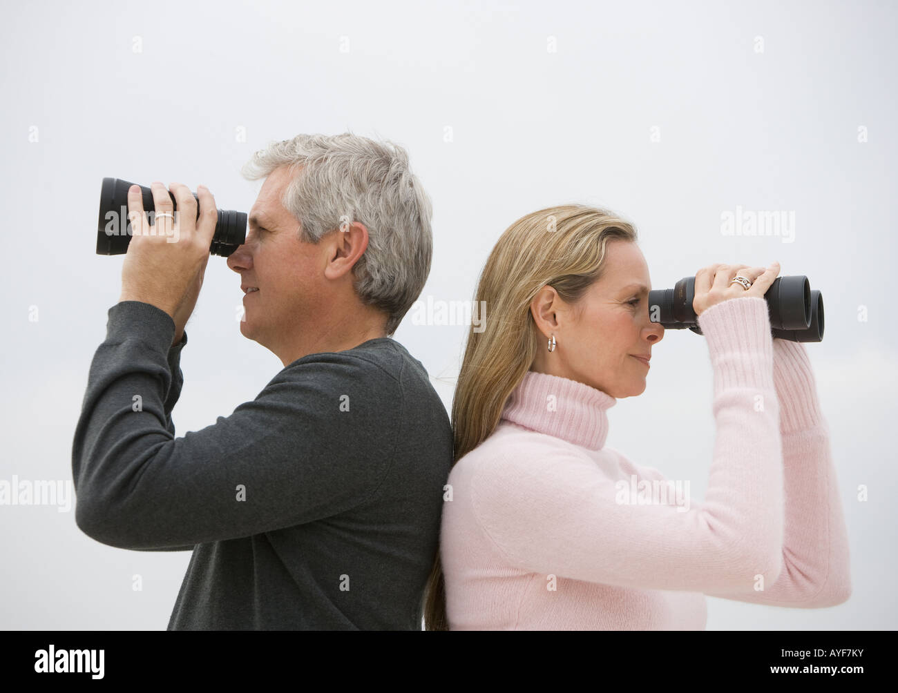 Couple looking through binoculars Stock Photo - Alamy