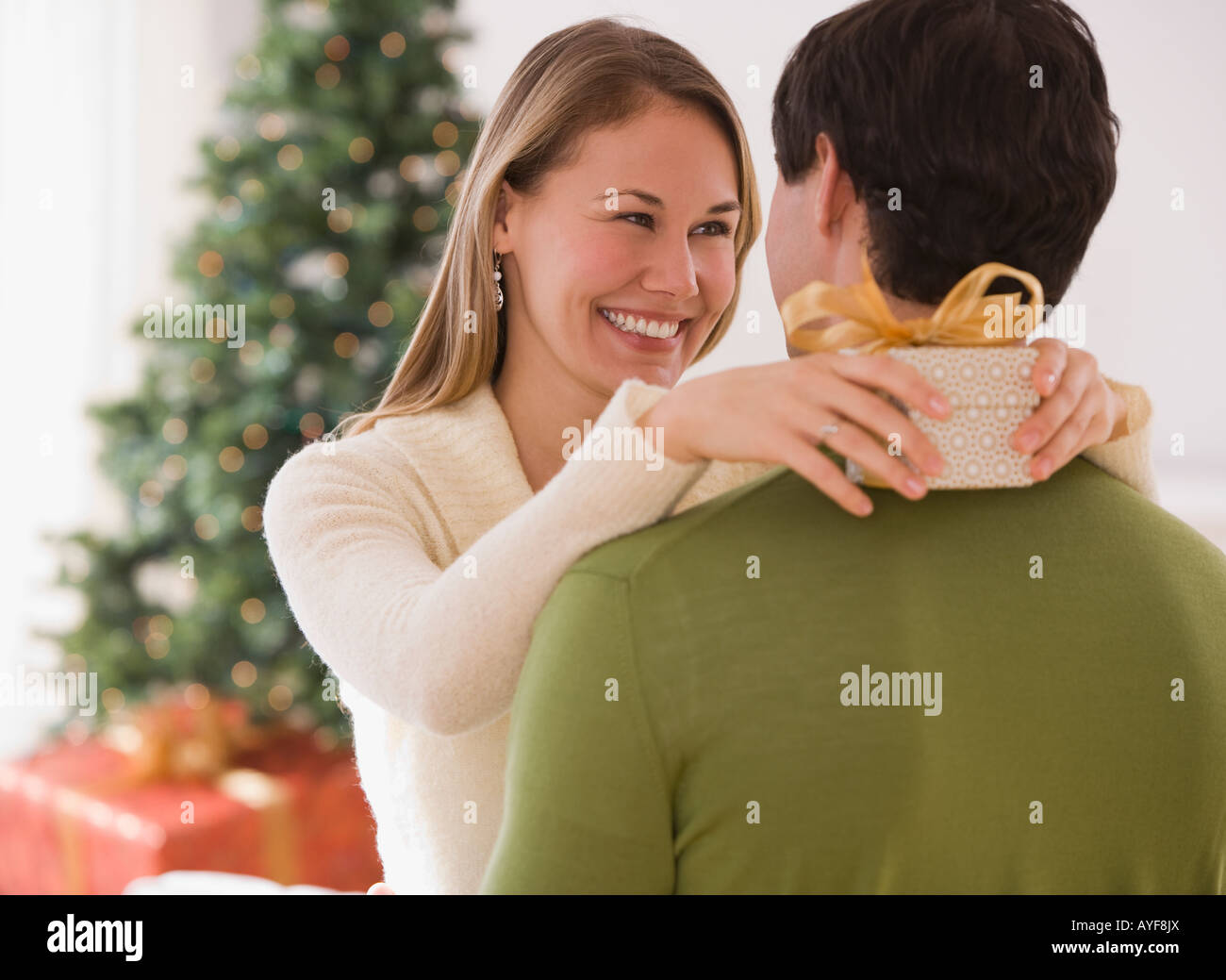 Woman holding gift and hugging husband Stock Photo - Alamy