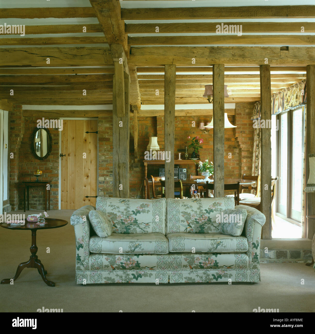 Patterned sofa in front of beamed wall with plaster removed in ...