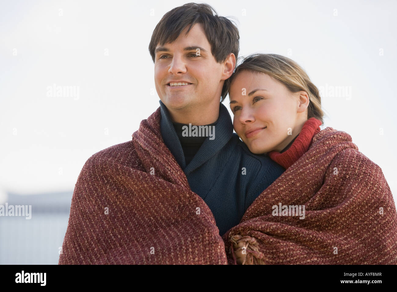 Couple wrapped in blanket Stock Photo - Alamy