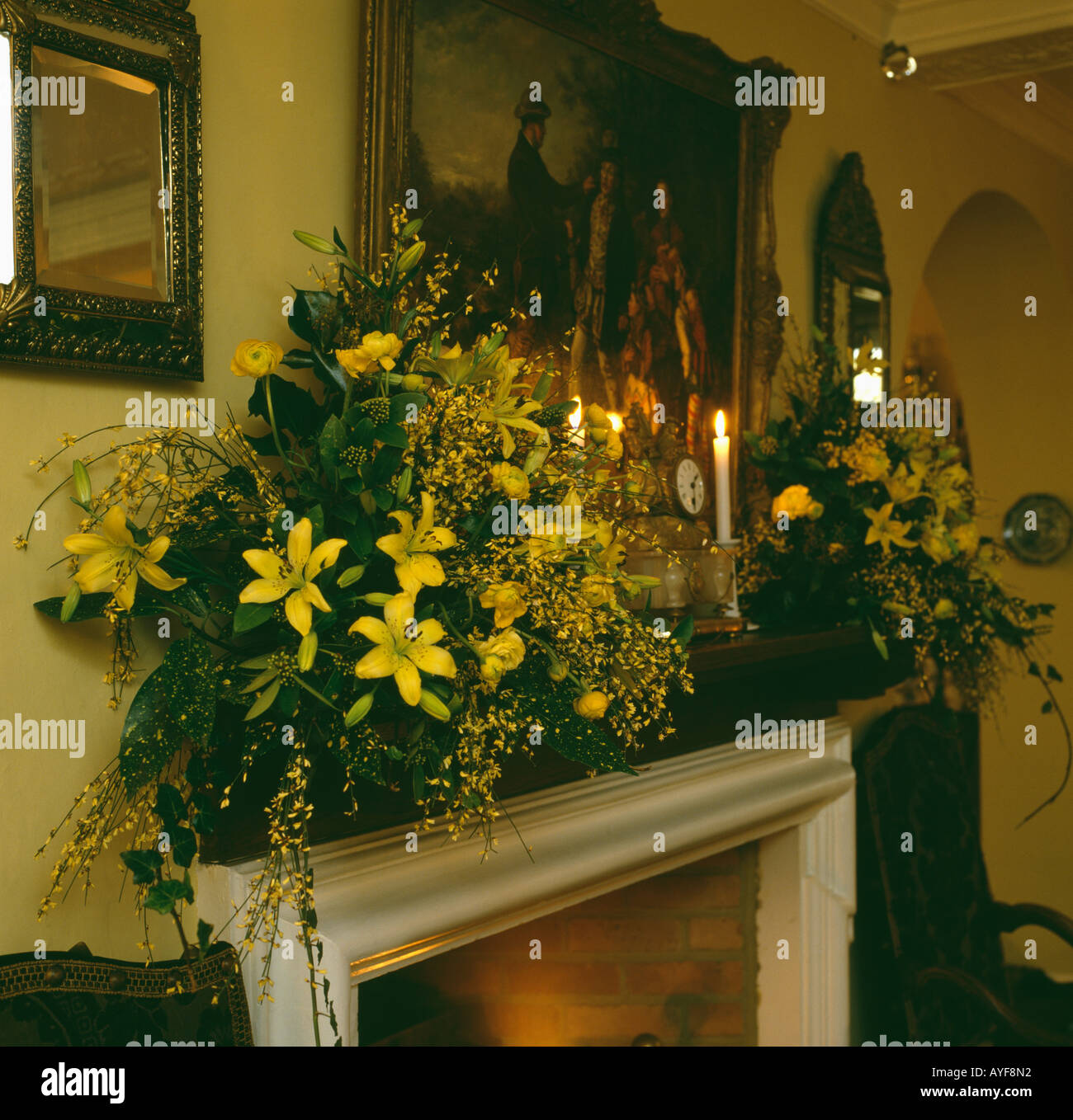 Yellow lilies and cistus in flower arrangement on mantelpiece in yellow ...