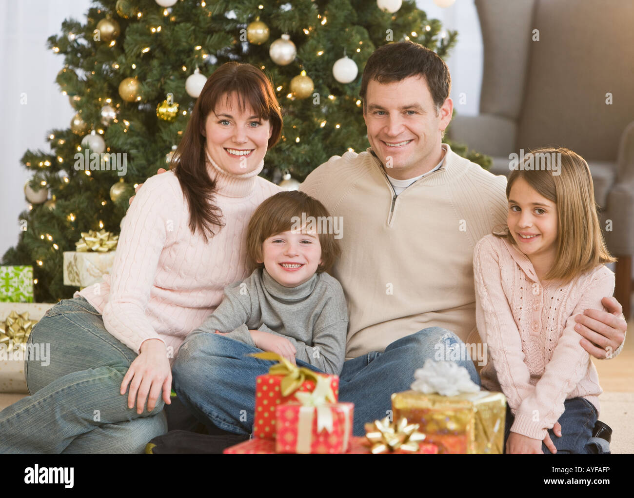 Family hugging in front of Christmas tree Stock Photo - Alamy