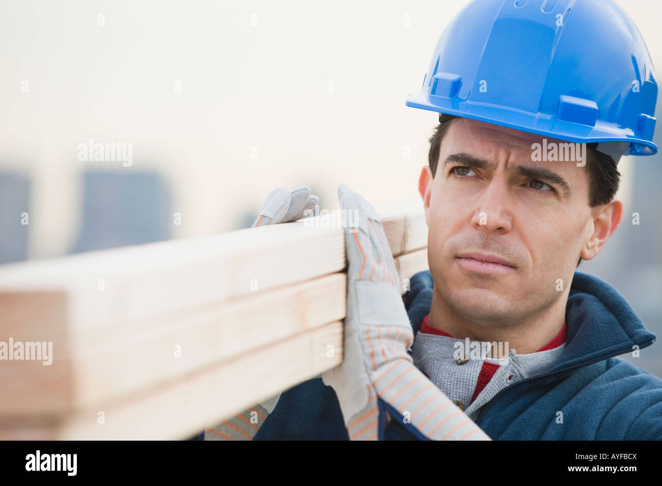 Male construction worker holding stack of lumber Stock Photo - Alamy