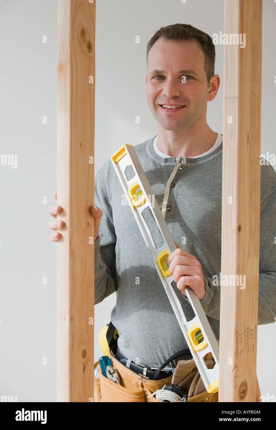 Male construction worker holding level tool Stock Photo - Alamy