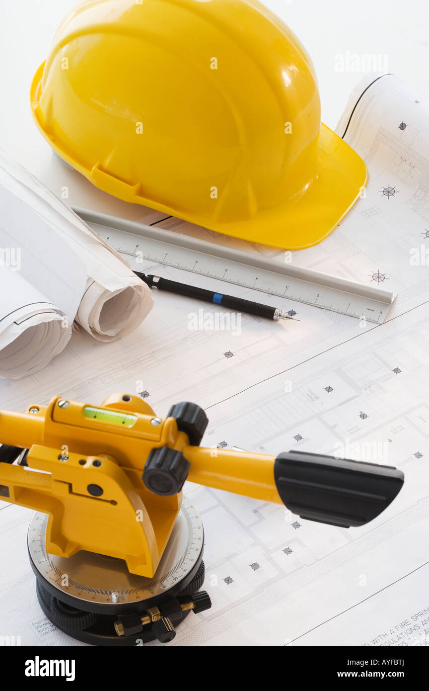 Hard hat and surveying equipment on blueprints Stock Photo - Alamy