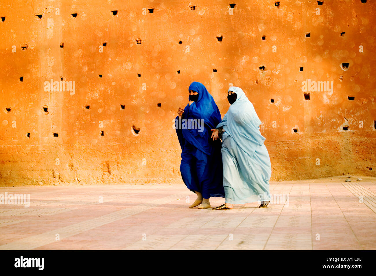 Muslim women wearing the traditional chador walk past the ramparts that ...