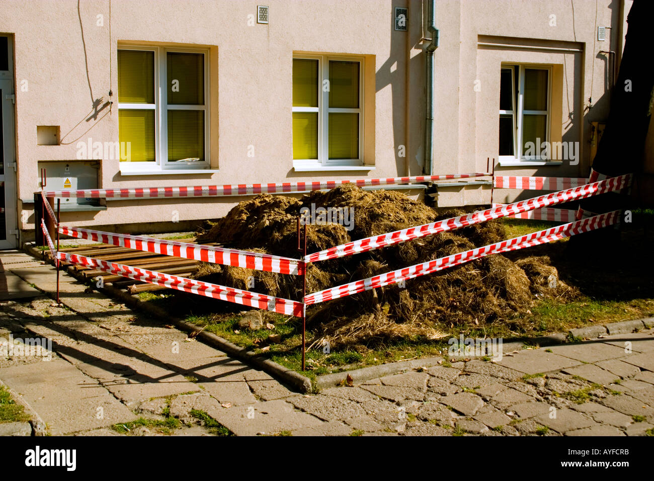 Red and white stripped warning tapes around a pile of construction dirt ...