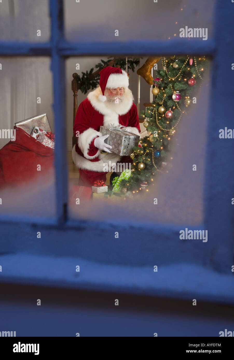 Santa Claus leaving gifts under Christmas tree Stock Photo - Alamy