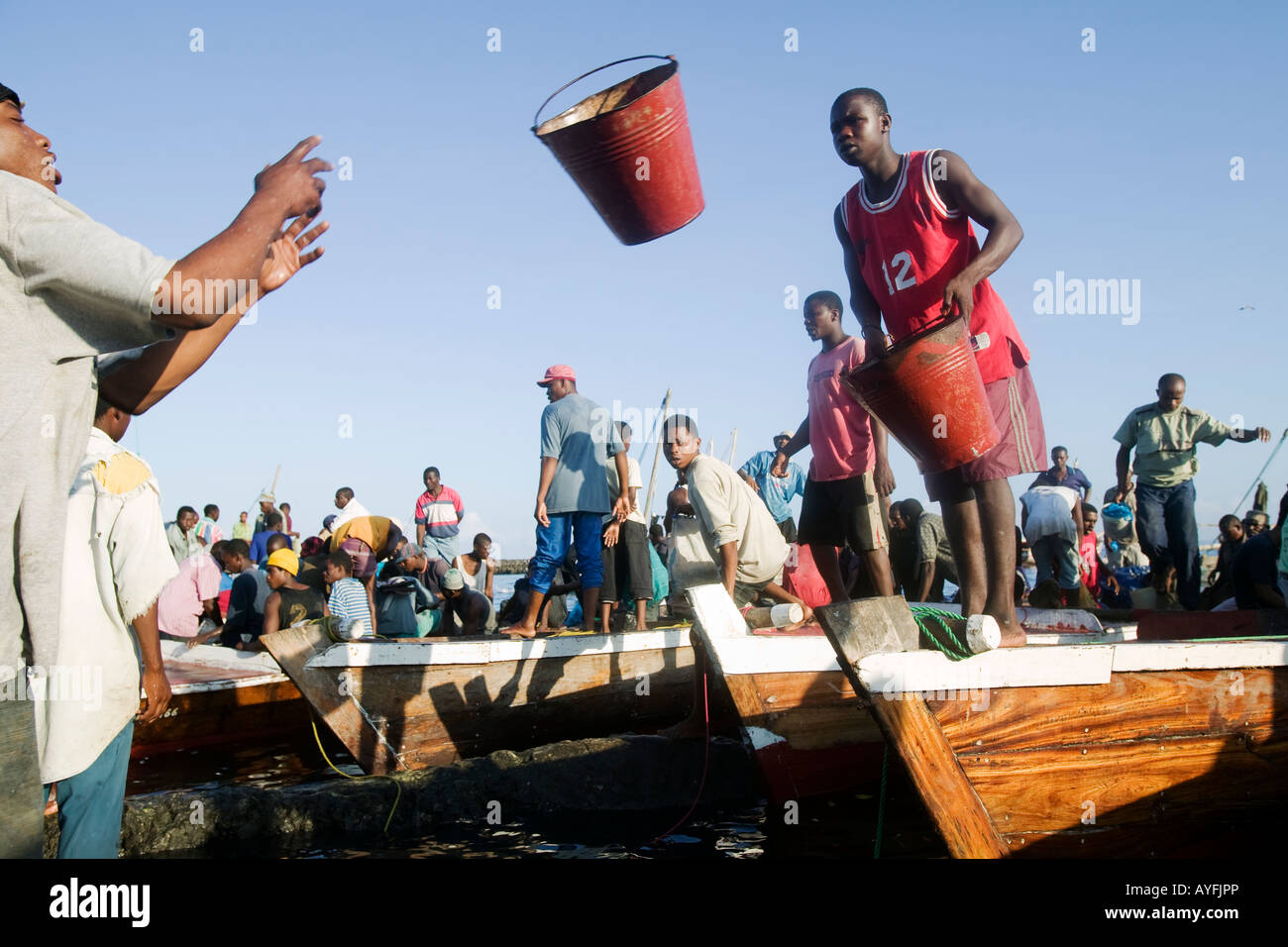 Africa Tanzania Zanzibar Stone Town Morning sun lights workers carrying ...