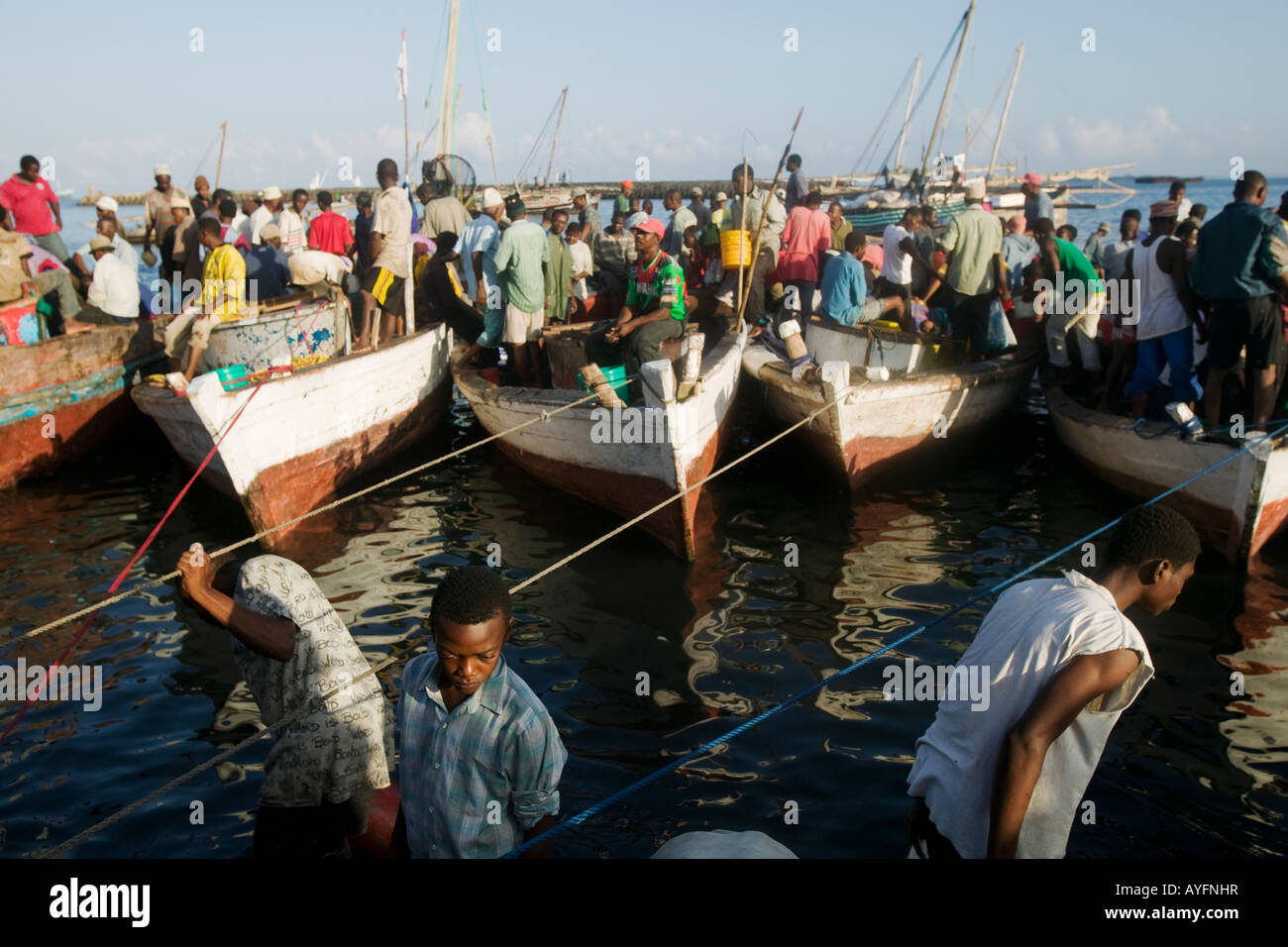 Africa Tanzania Zanzibar Stone Town Morning sun lights workers carrying ...