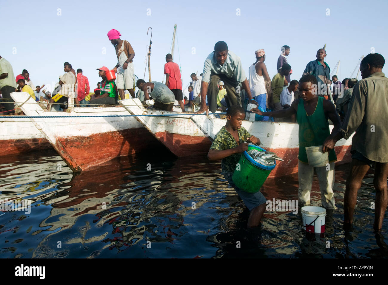 Africa Tanzania Zanzibar Stone Town Morning sun lights workers carrying ...