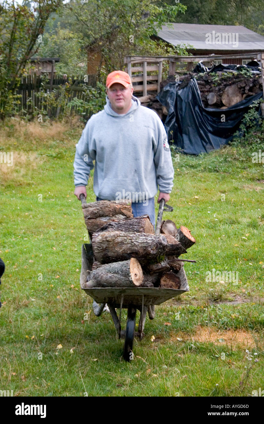 Man carrying wood in a wheelbarrow on the farm in Poland. Zawady Poland ...