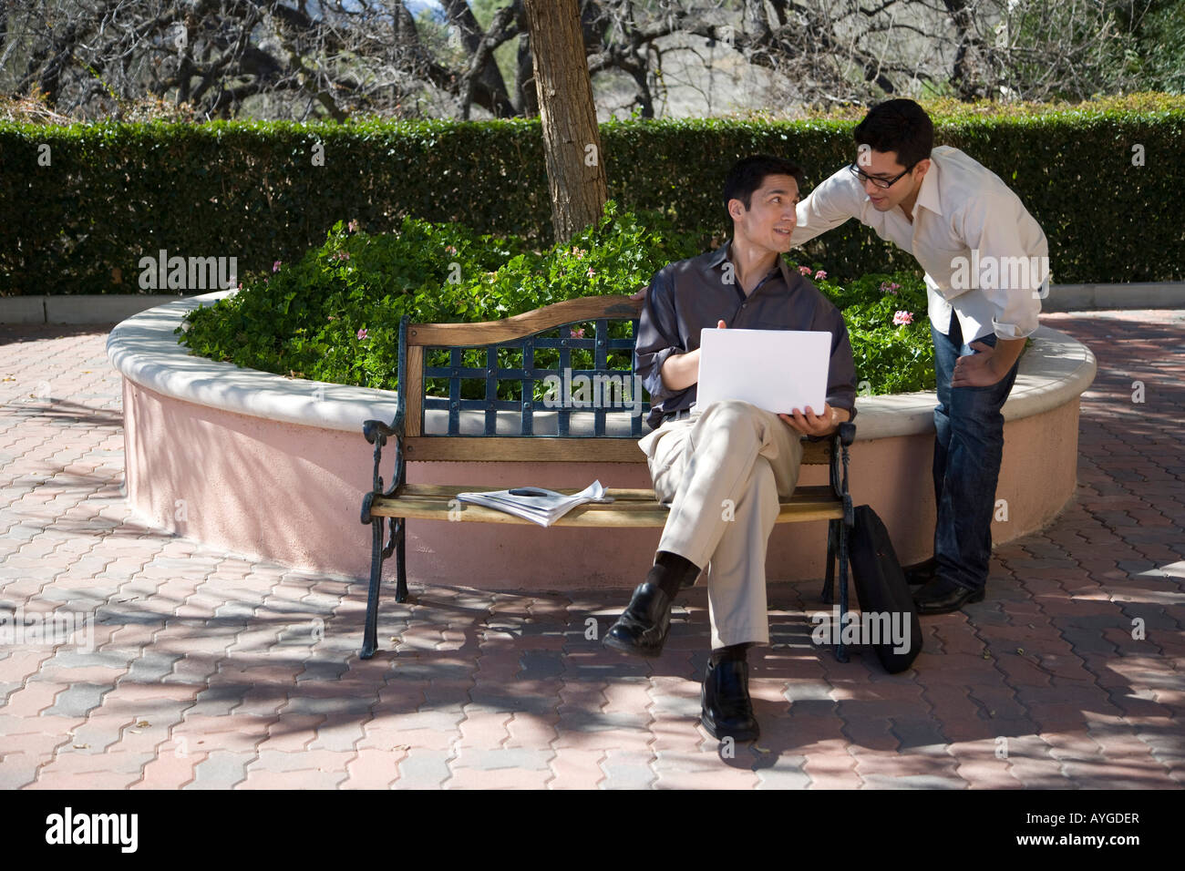 Business men review data on portable computer outside office building ...