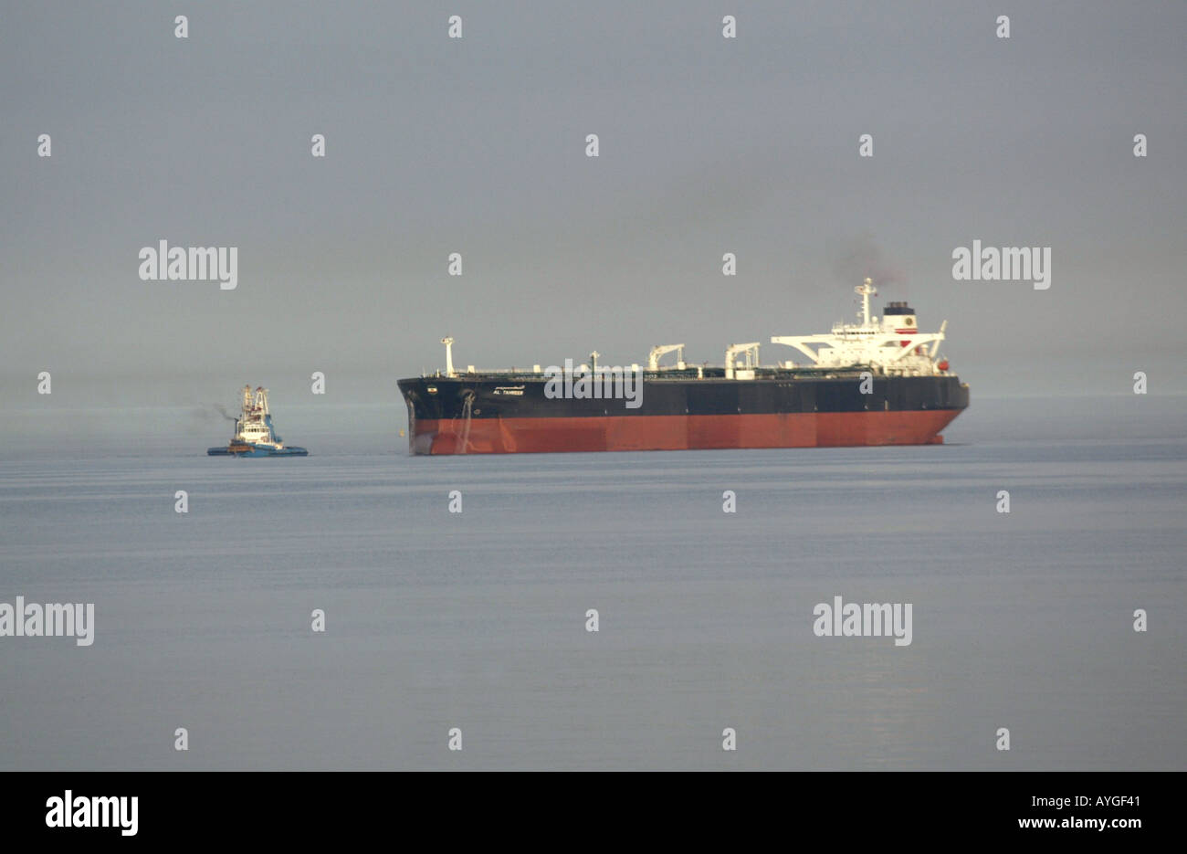 An empty oil tanker is pulled by a tug to an oil loading station along ...