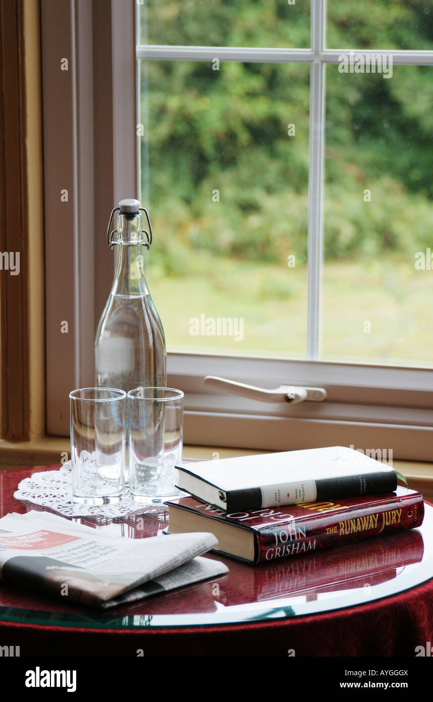 Books and a bottle of water on a table next to window in hotel room ...