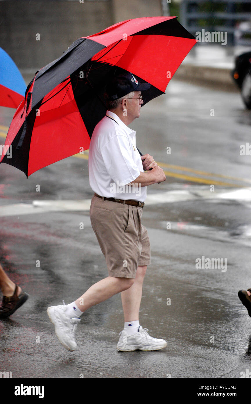 Pedestrian with umbrella protection is caught in rain storm on a public ...